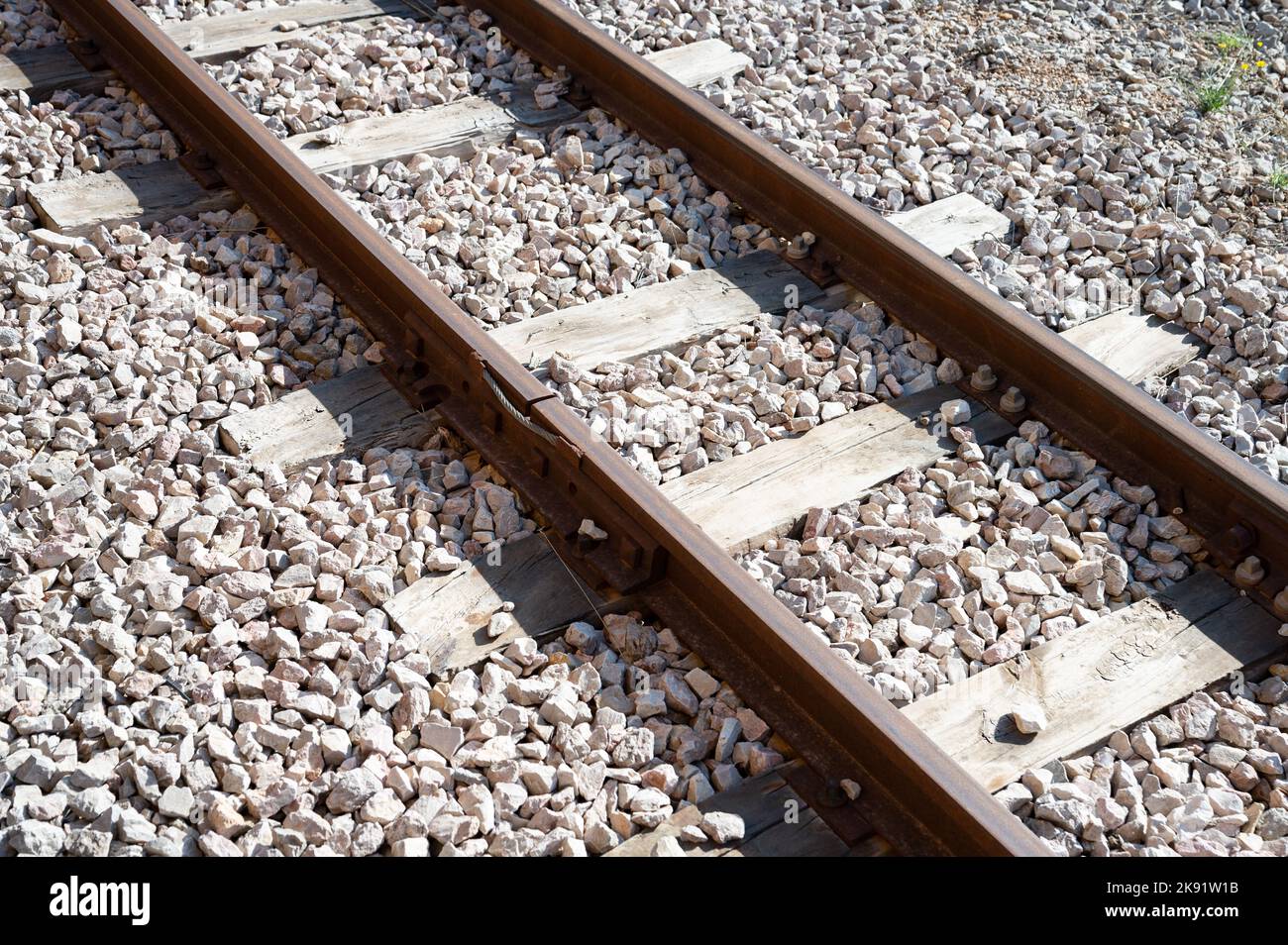 A closeup of an old train railway with wooden sleepers and stone floor ...