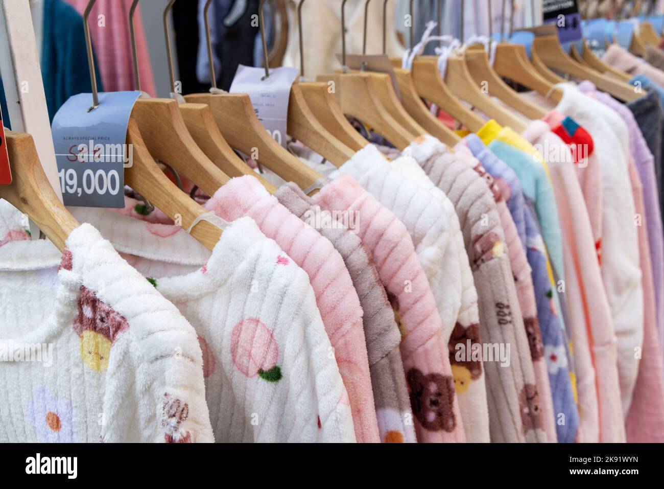 A shopping rank filled with clothes, pajamas and robes. Bunch of ...