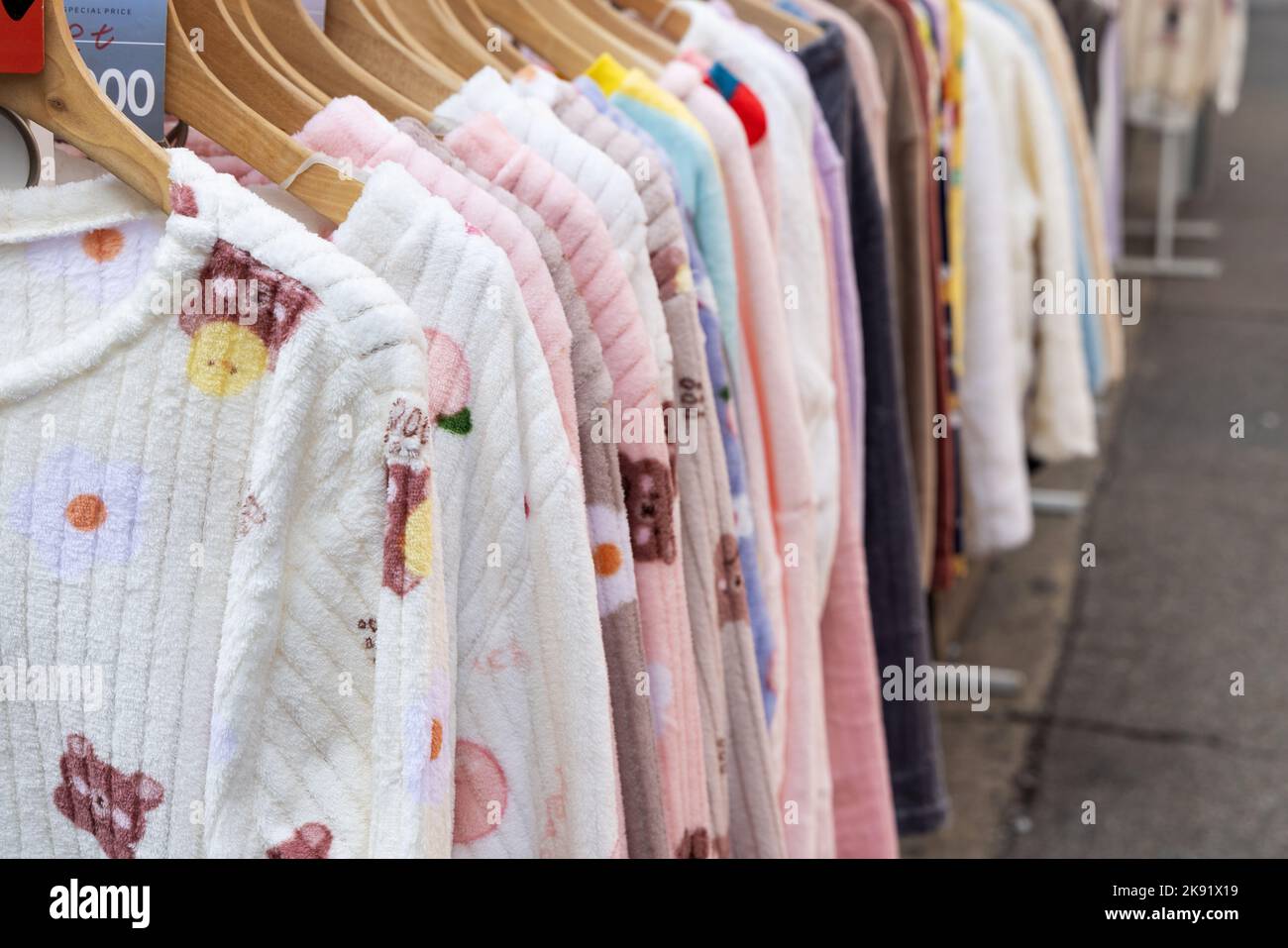 A shopping rank filled with clothes, pajamas and robes. Bunch of ...
