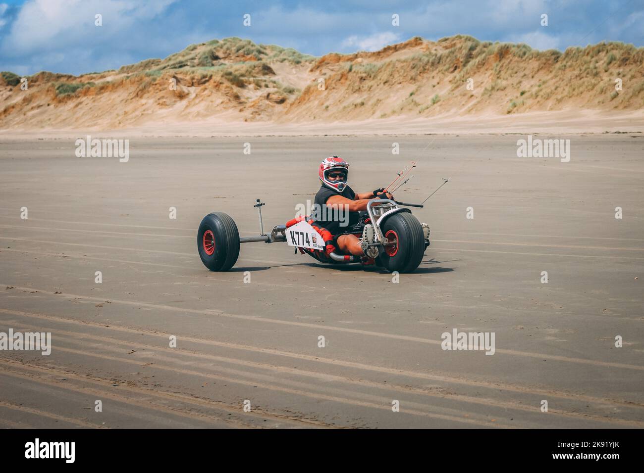 A person riding a kite buggy in a desert wearing a protective helmet ...