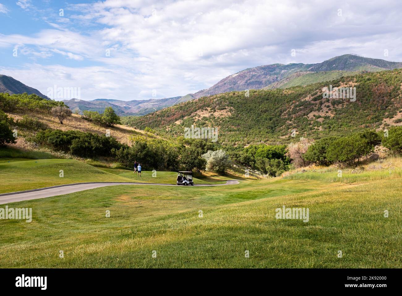 The natural landscape with the people and golf cart driving on the road ...