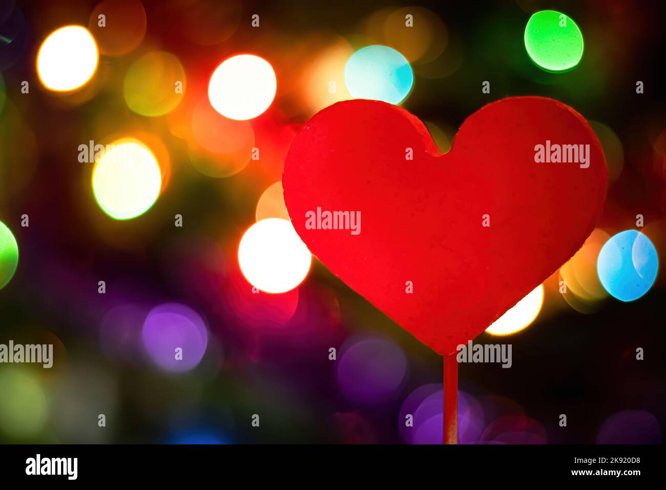 Red heart on backdrop of bright multi-colored lights. Background for ...