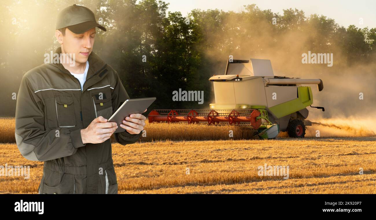 A farmer with digital tablet controls an autonomous harvester on a ...