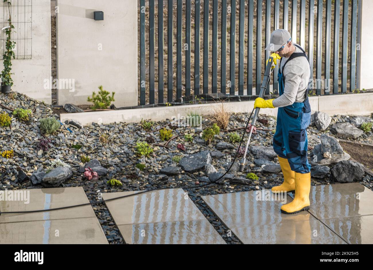 Caucasian Middle Aged Worker Washing Concrete Tiles in the Yard with a ...