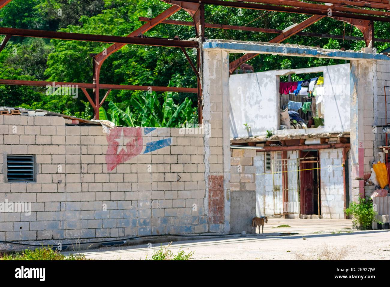 A collapsed abandoned warehouse with a Cuban flag on the exterior ...