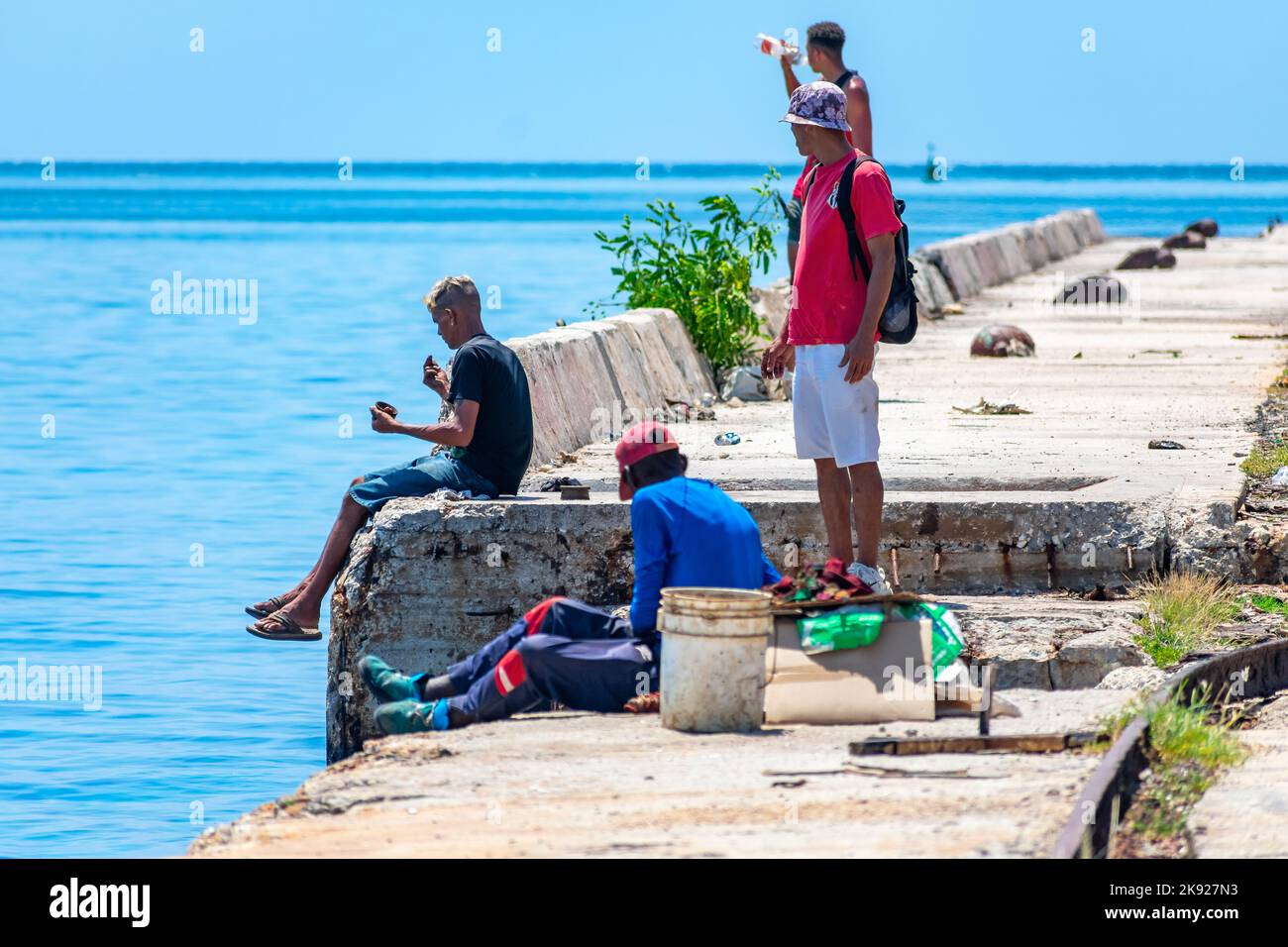Cuban men fishing in a run-down pier in the city waterfront Stock Photo ...