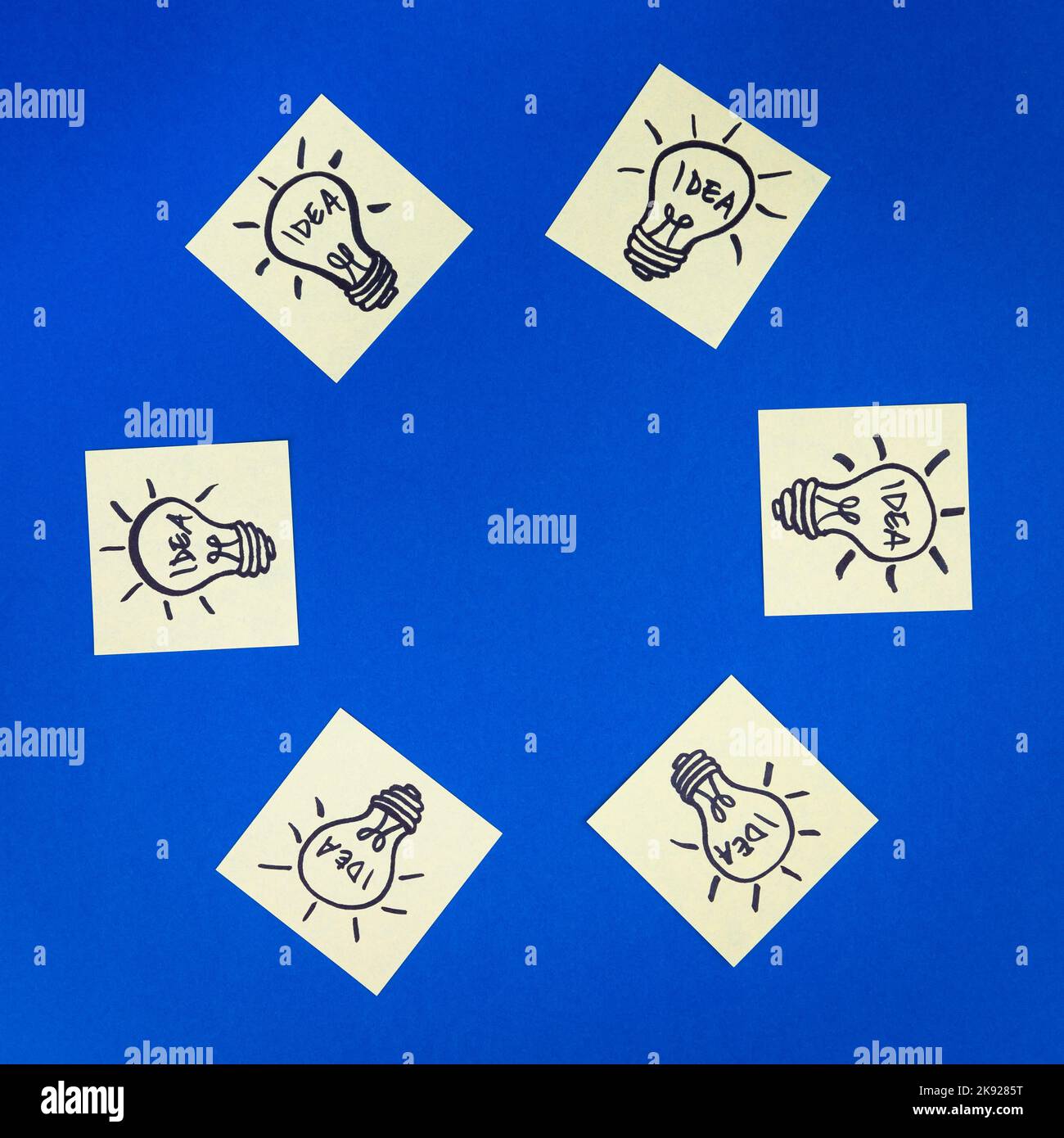 Light bulbs drawn on sticky notes placed in a circle with empty space ...