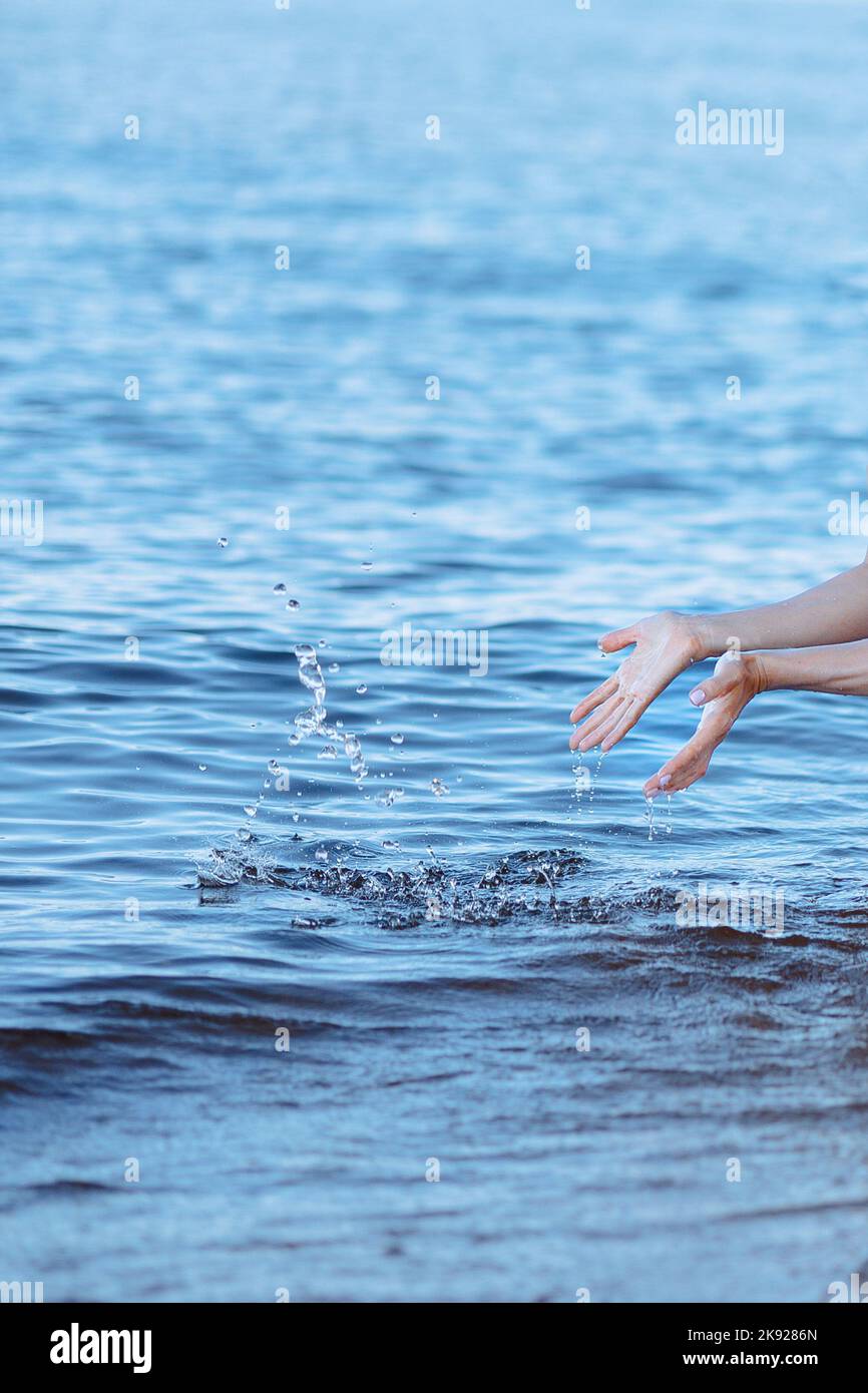 Female hands with splashes of clear blue fresh water in sea. Air ...
