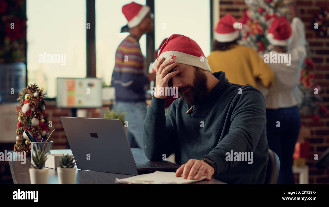 Stressed person trying to work in festive decorated office, being ...