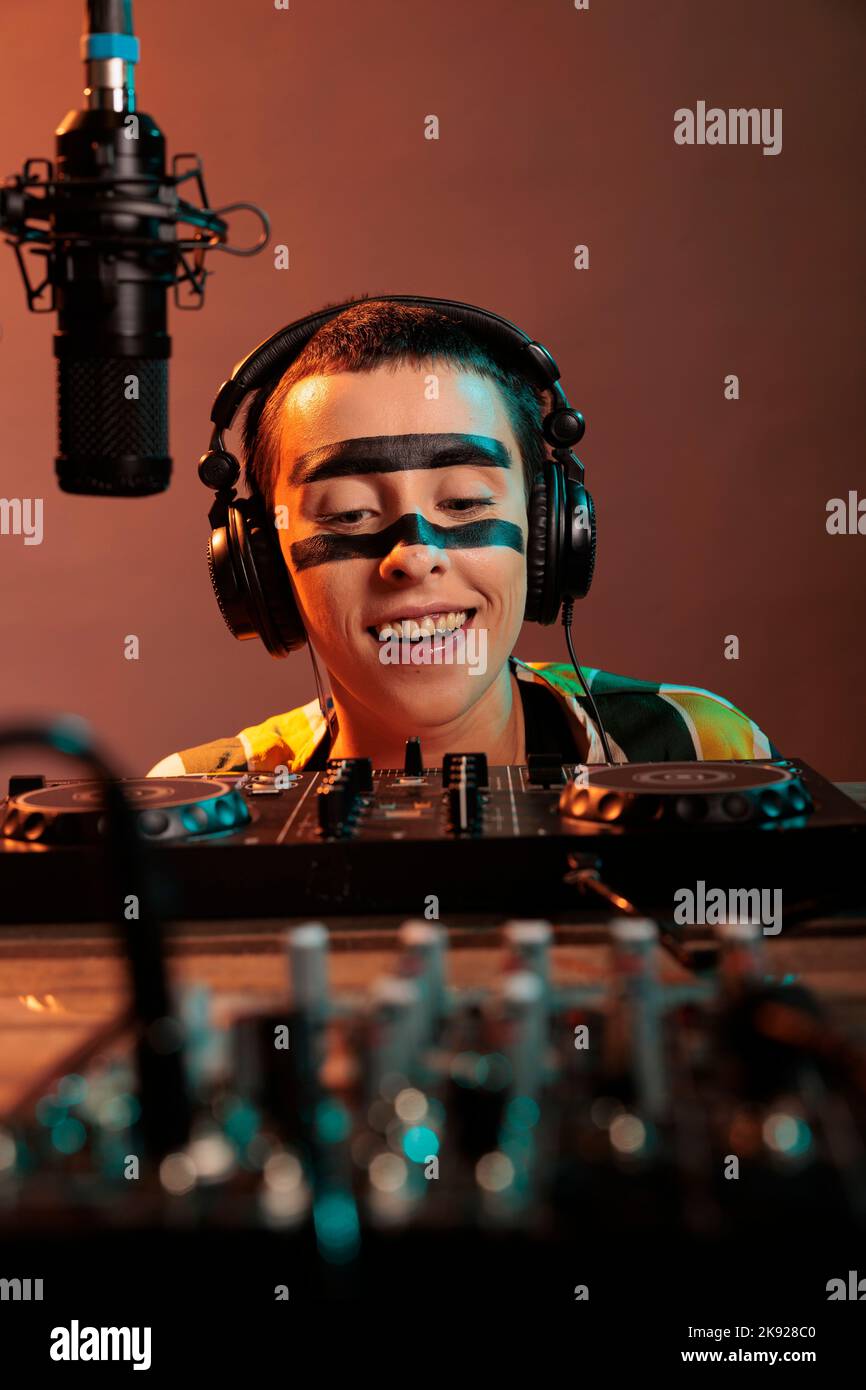 Crazy female artist acting silly at mixer, looking closely at control ...