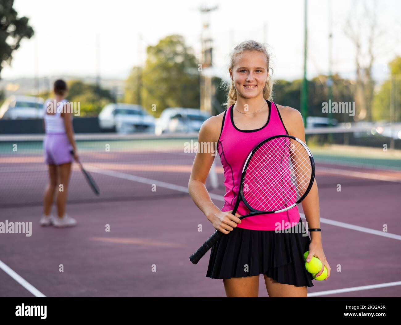 Happy young woman posing with racket and ball on court Stock Photo - Alamy