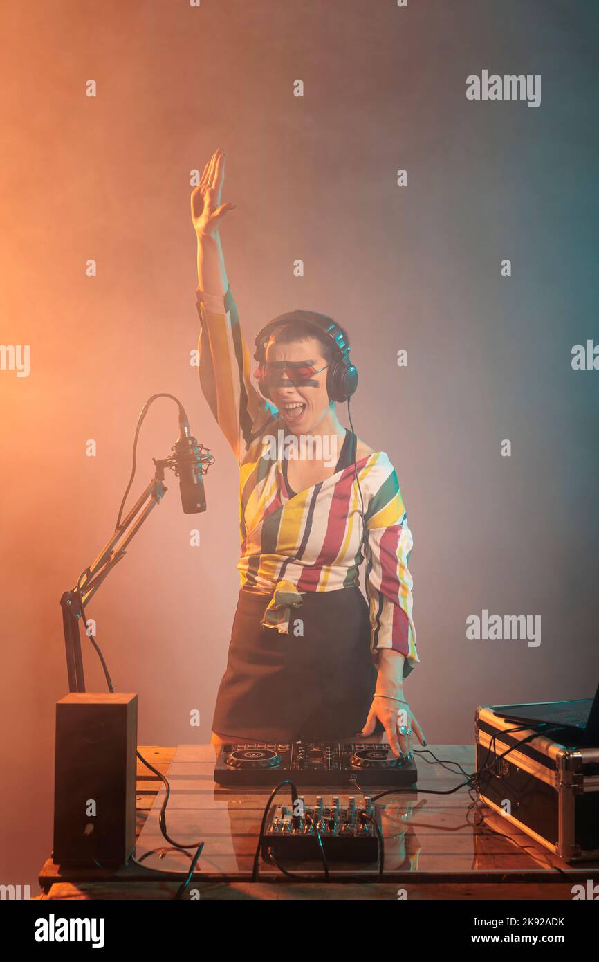 Female DJ mixing music with audio equipment, using turntables to ...