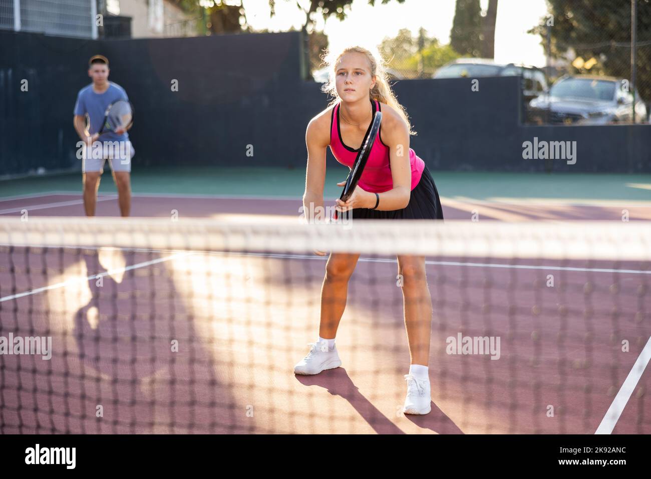 Sports active woman and her male partner playing tennis on court ...