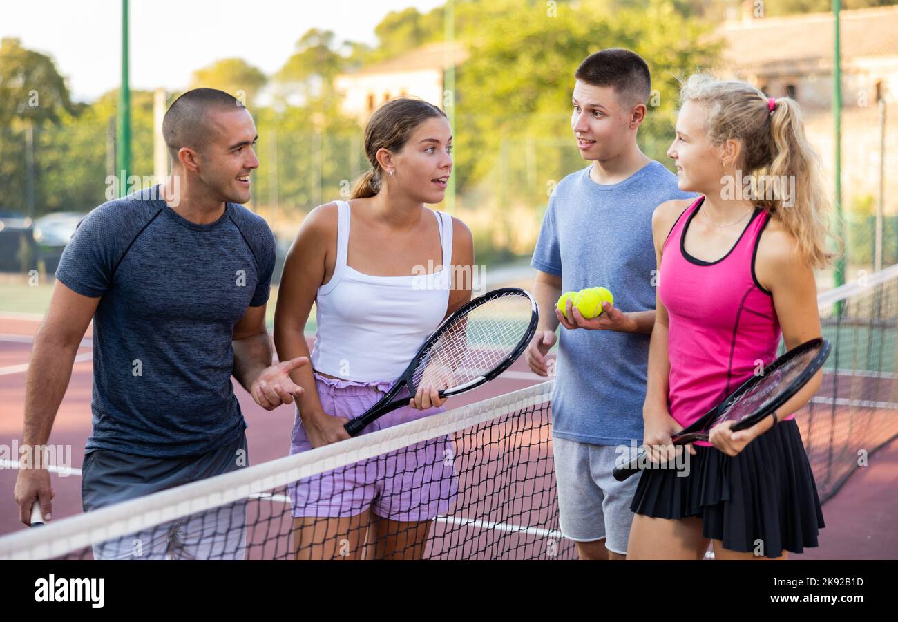 Friendly people chatting on outdoor tennis court Stock Photo - Alamy