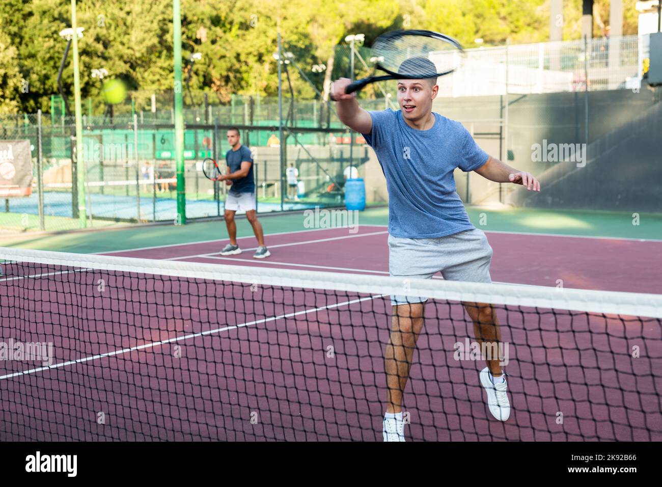 Young teenage player training on court. Boy using racket to hit ball ...