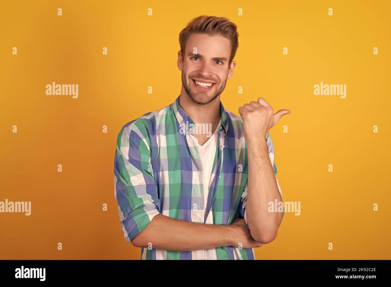Your advert here. Happy man pointing thumb yellow background. Place ...