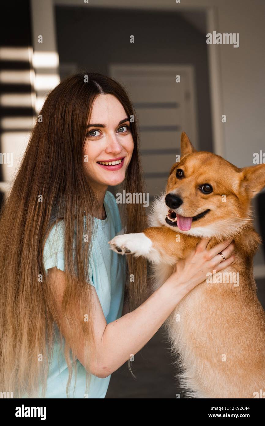 Domestic Corgi dog with girl owner. Young woman sitting on the floor ...