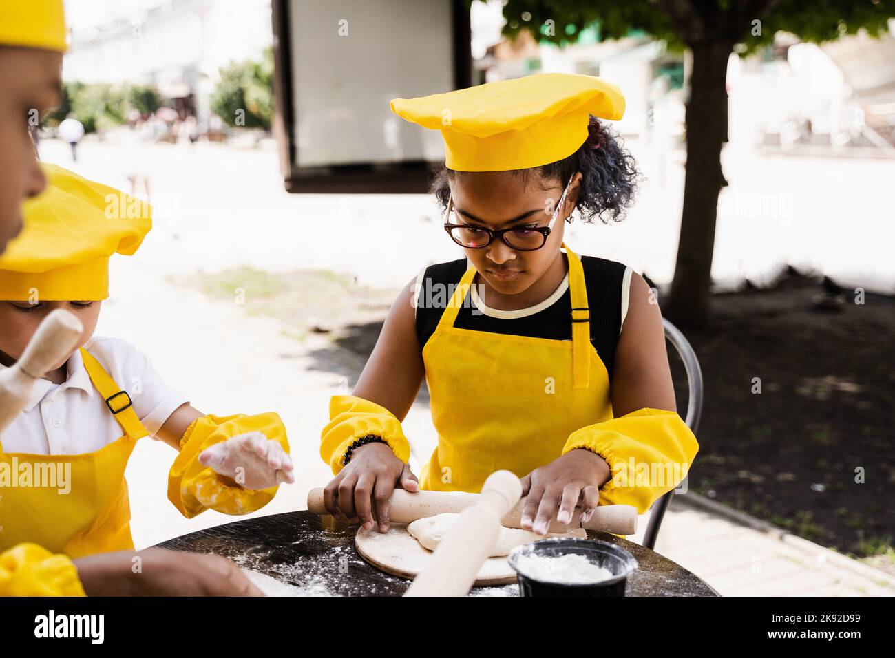Multiethnic cooks children in yellow chefs hat and apron cooking dough ...