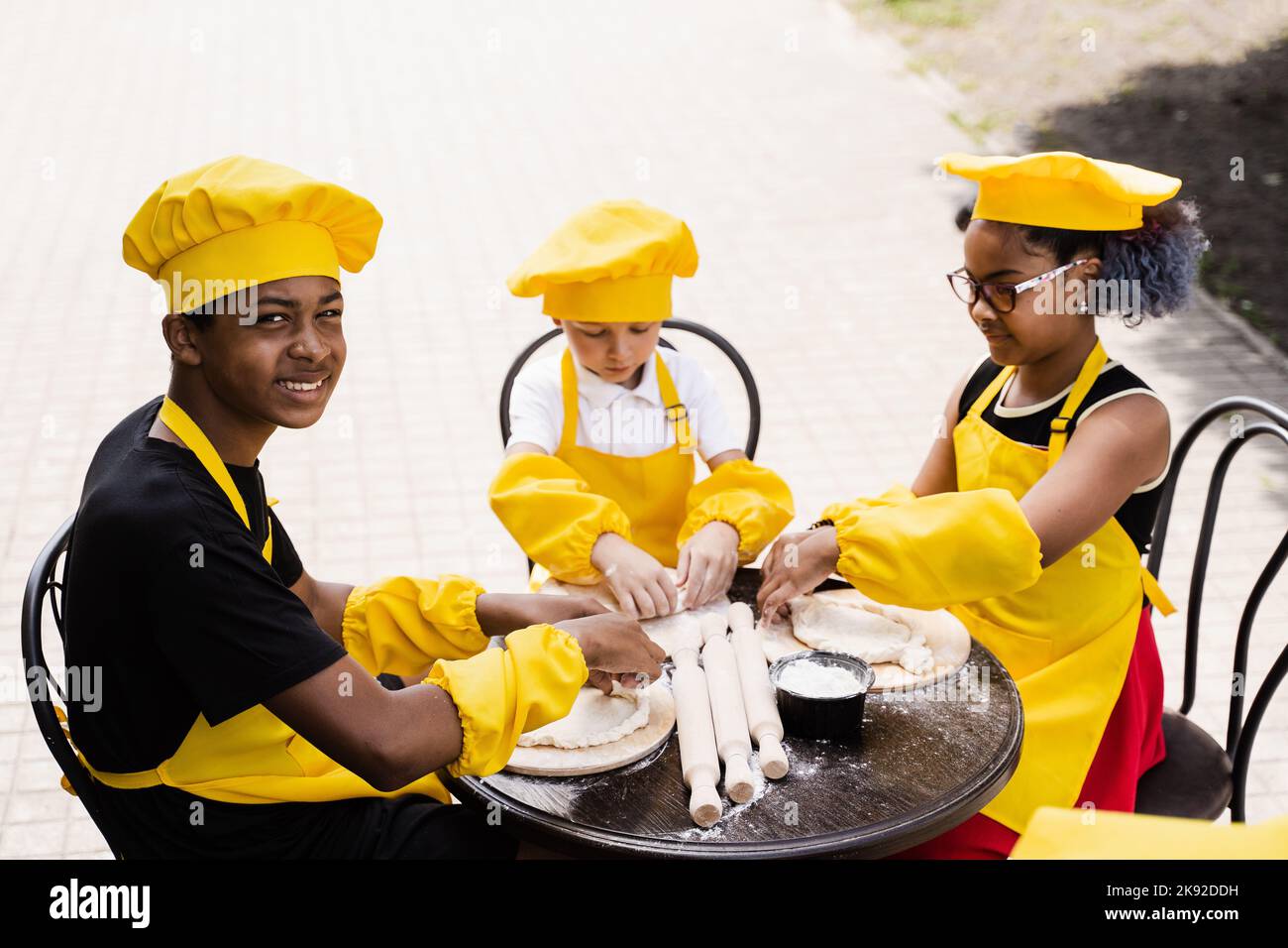 Multinational company of children cooks in yellow uniforms cooking ...