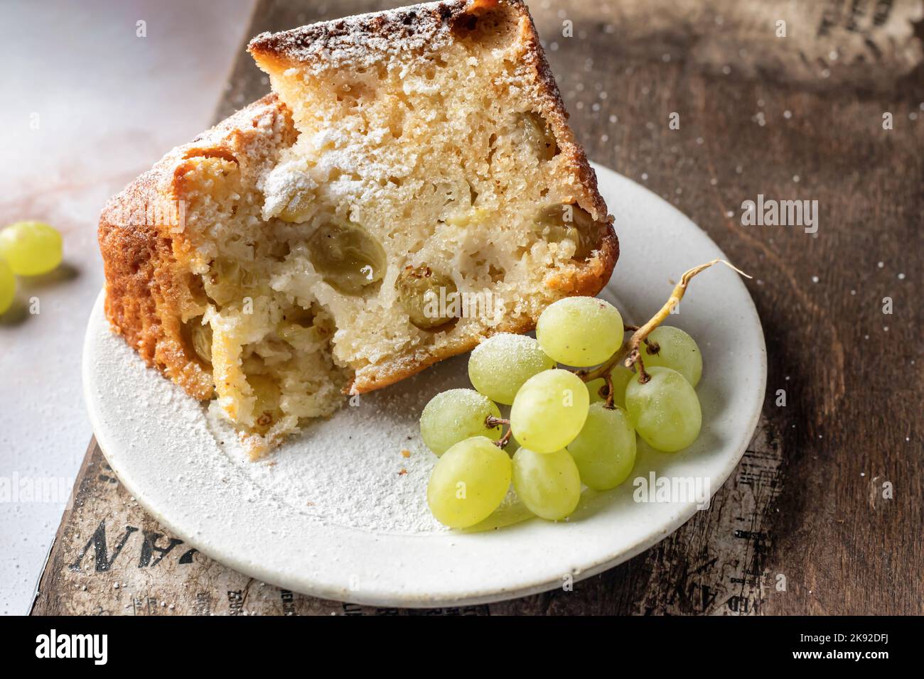 Slices of grape cake pie served with fresh grapes and poudered sugar on ...