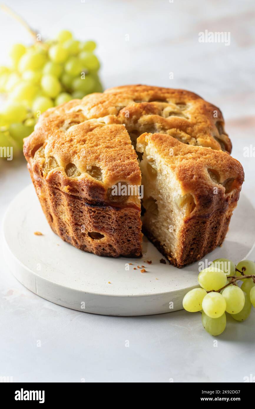 Homemade biscuit cake or pie with white fresh grapes on a white marble ...