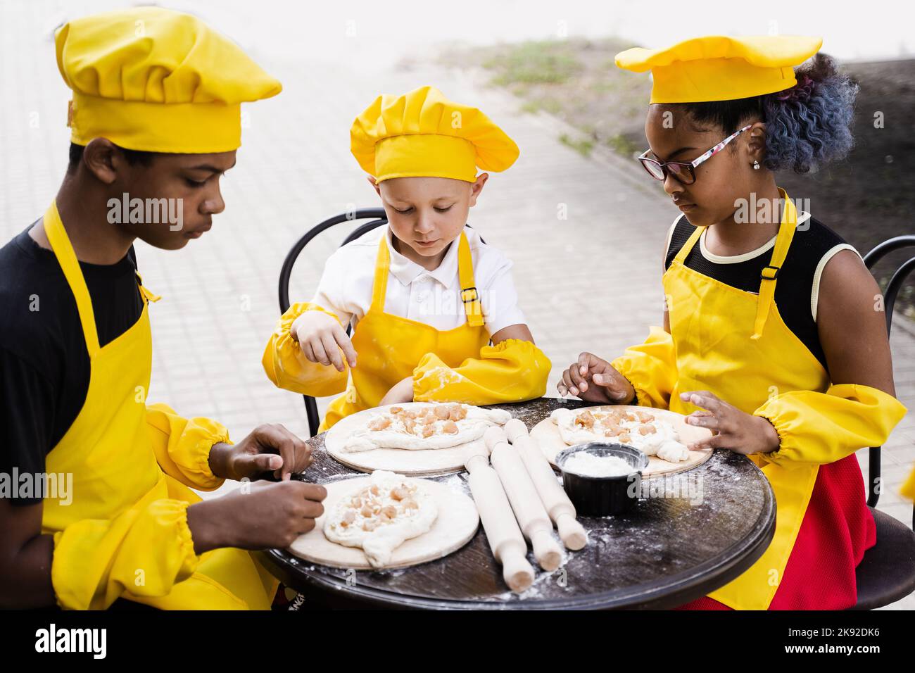 Happy company of multiethnic children cooking dough. Childhood cook ...
