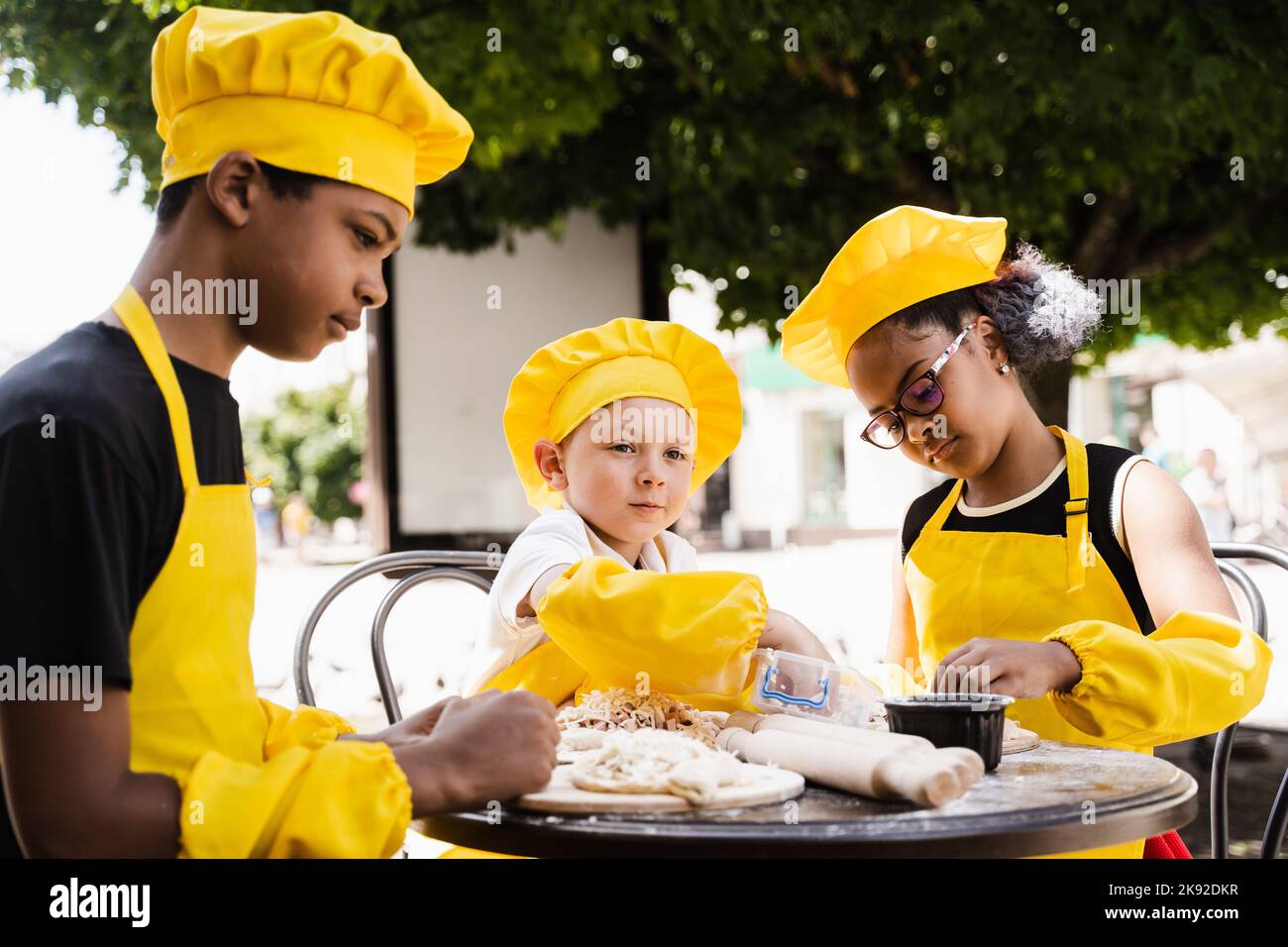 Happy company of multiethnic children cooking dough. Childhood cook ...
