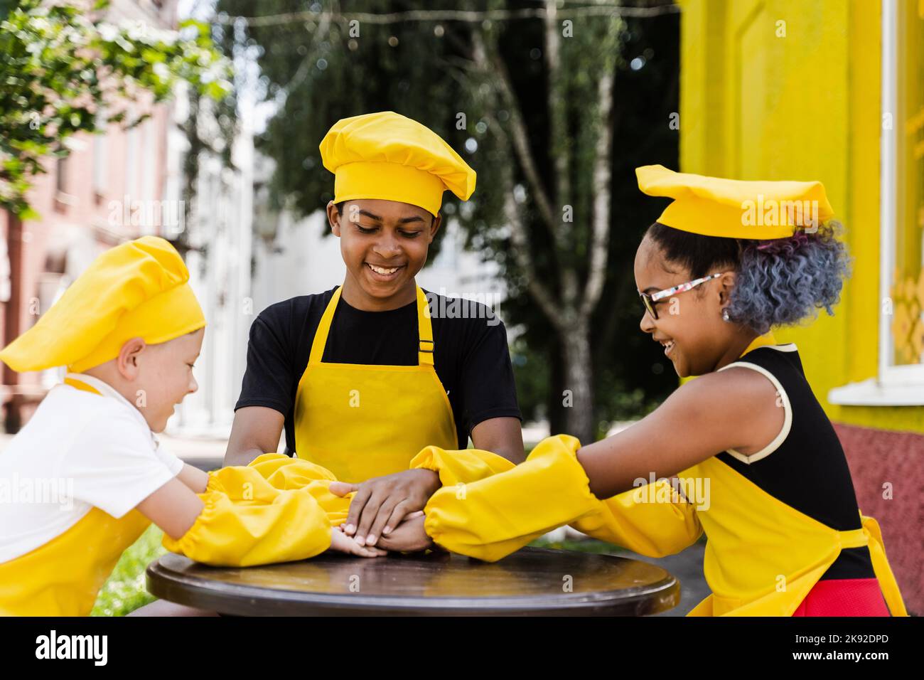 Teambuilding of multinational children cooks in chefs hat and yellow ...
