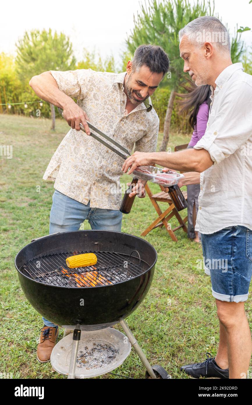 Multiethnic middle-aged people around the barbecue smiling happy and ...