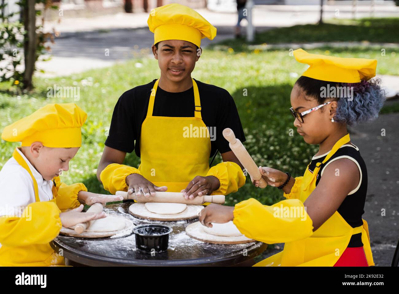 Multinational company of children cooks in yellow uniforms cooking ...