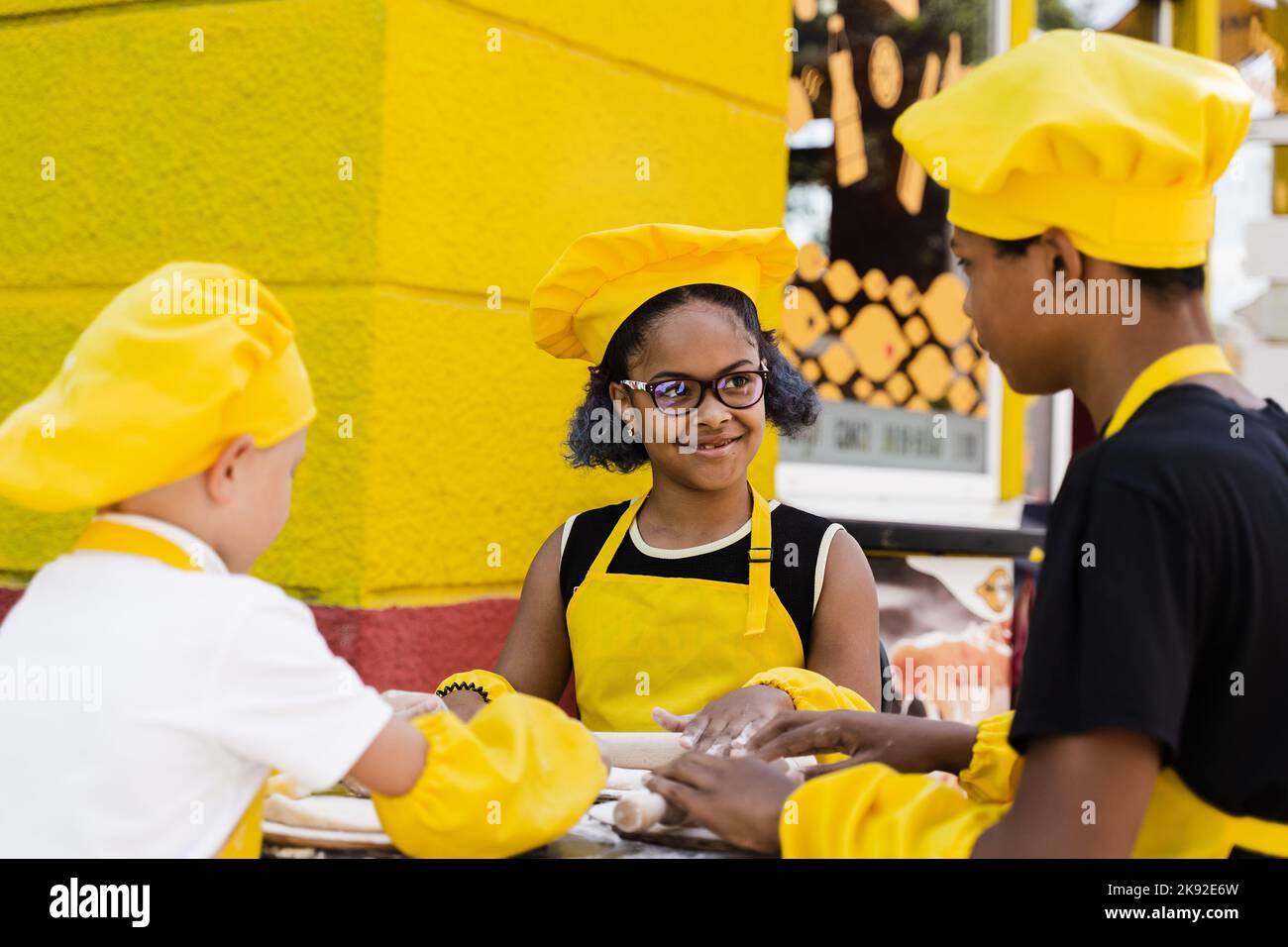 Multinational company of children cooks in yellow uniforms cooking ...