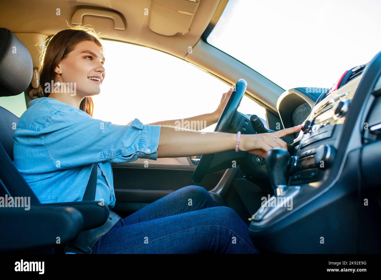 pretty woman singing while driving a car on road trip on summer day ...