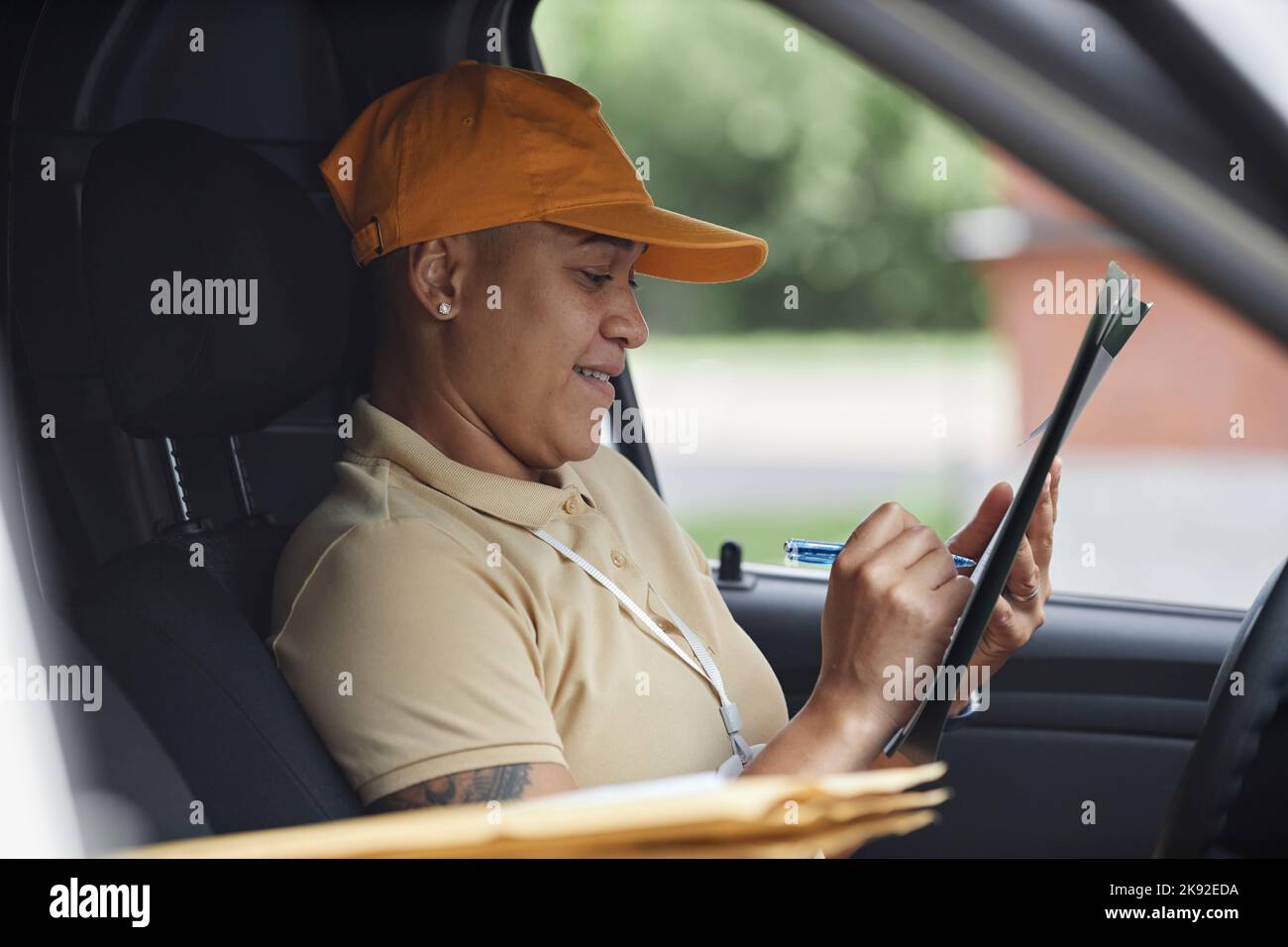 Side view portrait of female delivery driver filling postal forms in ...