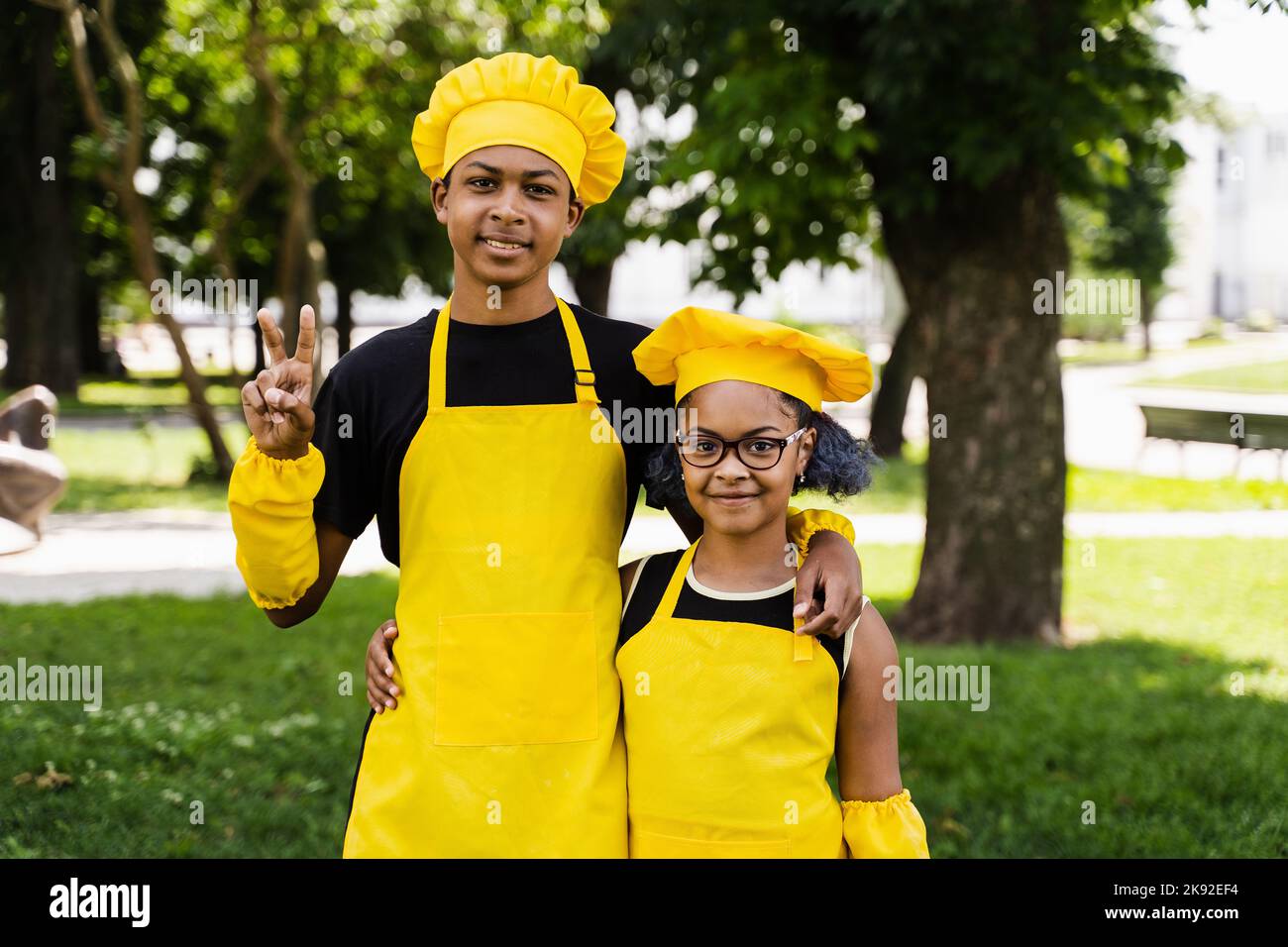 African children cooks in chefs hat and yellow uniforms smiling outdoor ...