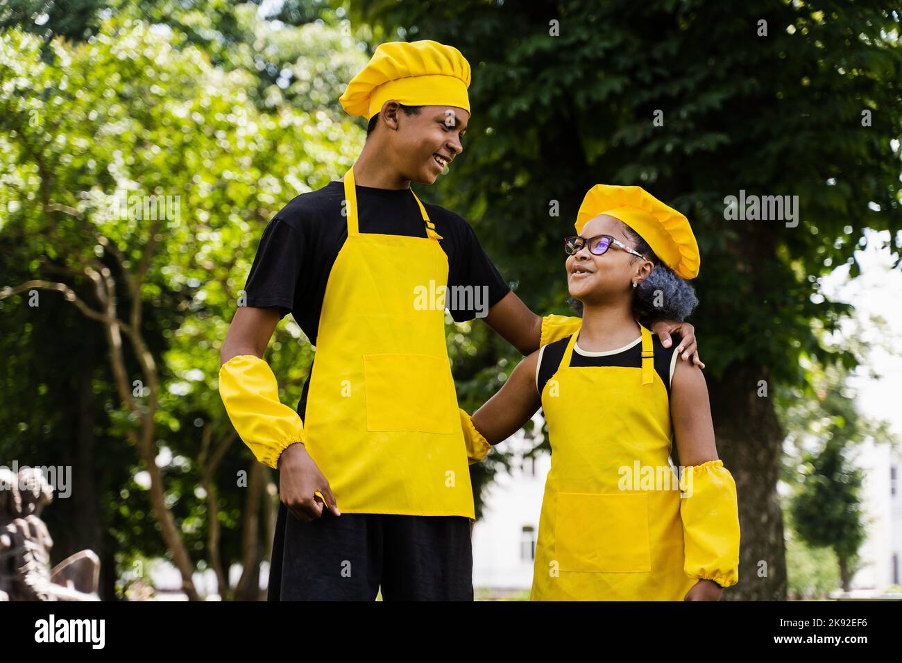 African children cooks in chefs hat and yellow uniforms smiling outdoor ...