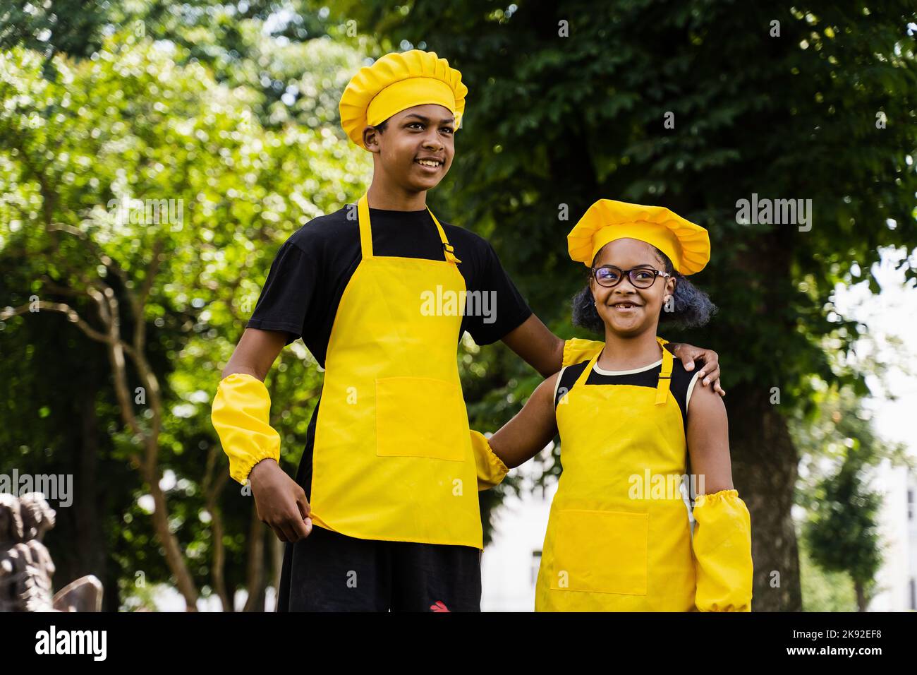 African children cooks in chefs hat and yellow uniforms smiling outdoor ...