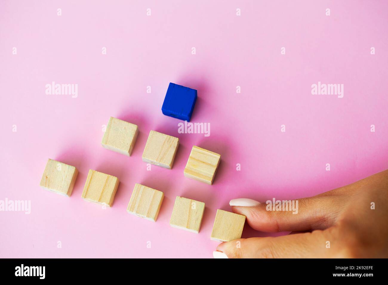 Woman hand arranging empty wood block and copy space on pink background ...