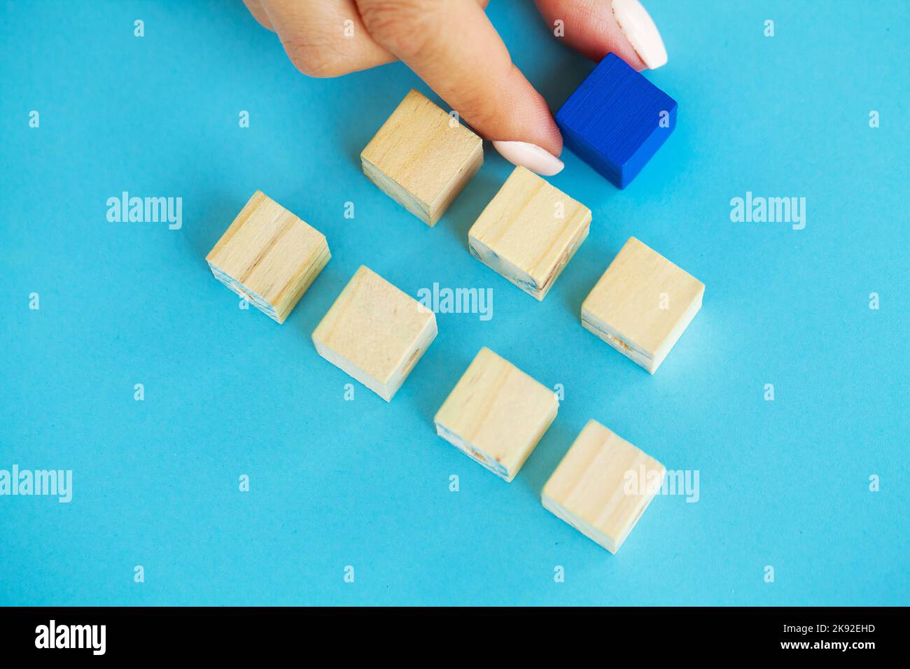 Wooden blocks with a human hand placing one cube at the top on blue ...