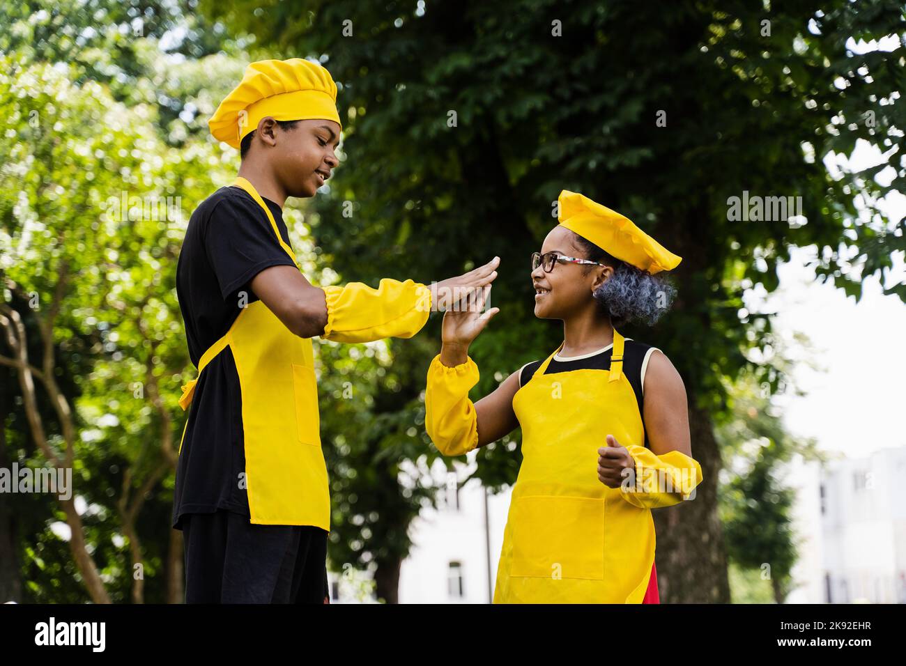 Black african cooks children in yellow chefs hat and apron clap each ...