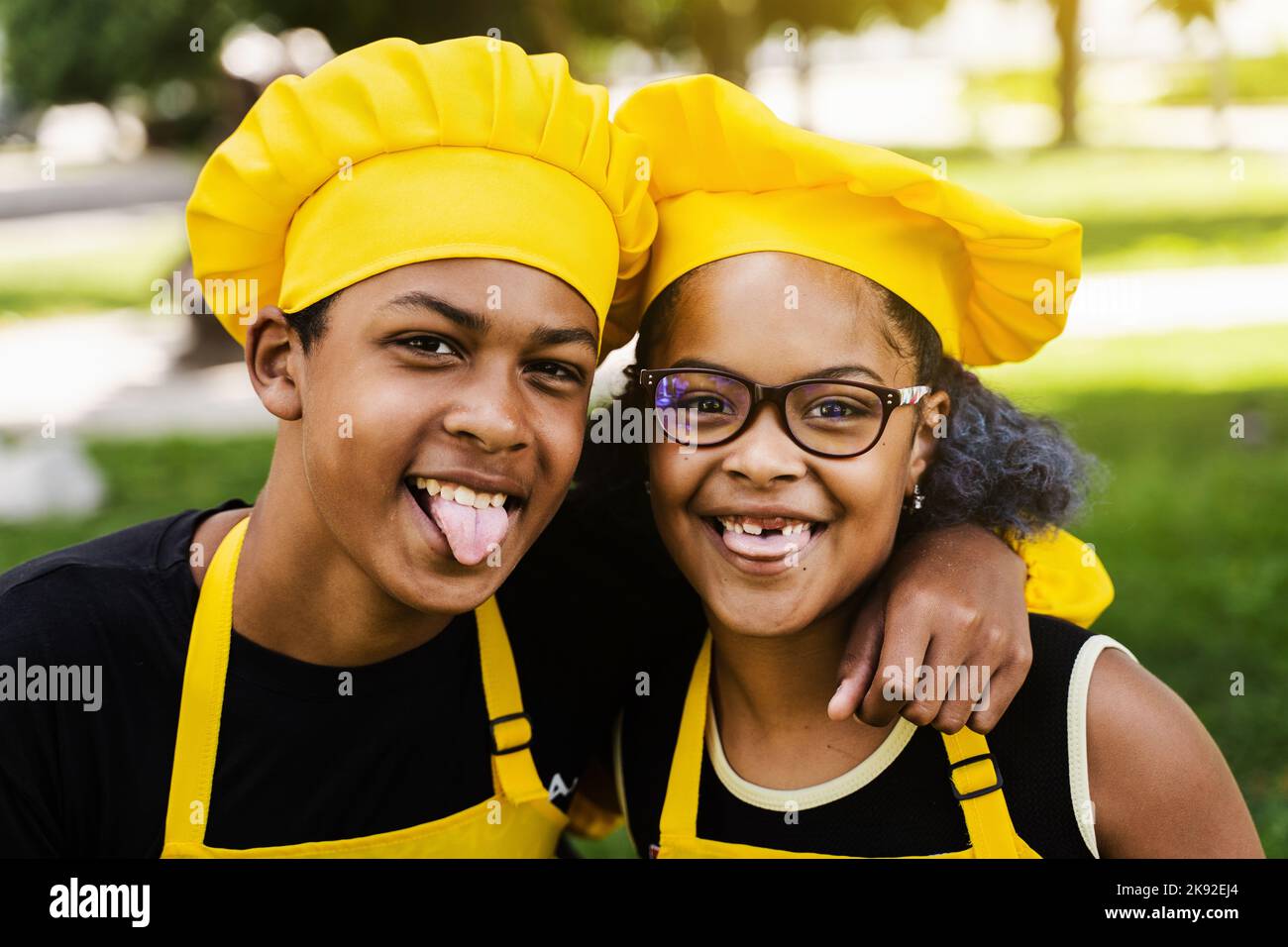 African children cooks in chefs hat and yellow uniforms grimacing and ...