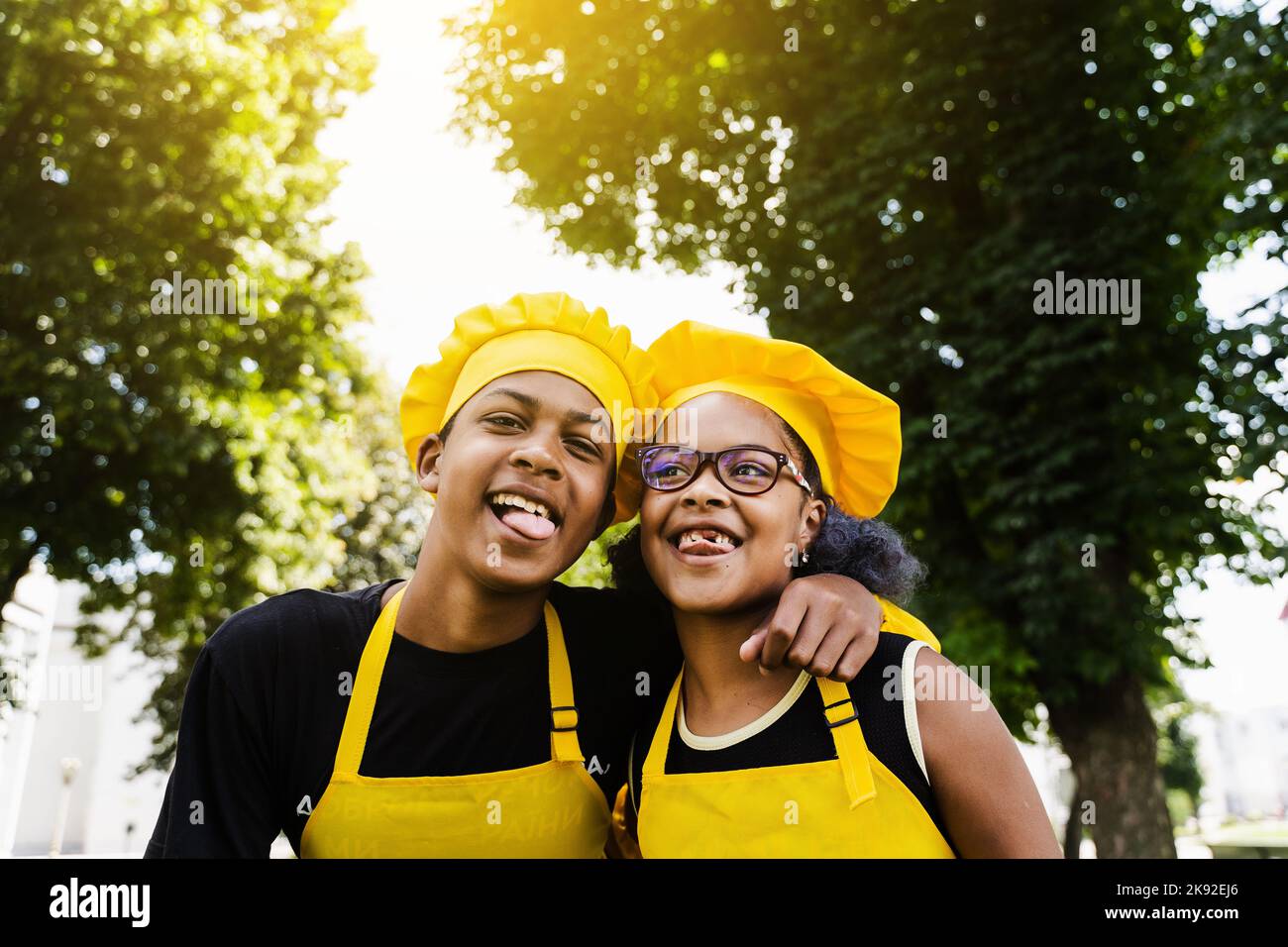 African children cooks in chefs hat and yellow uniforms grimacing and ...