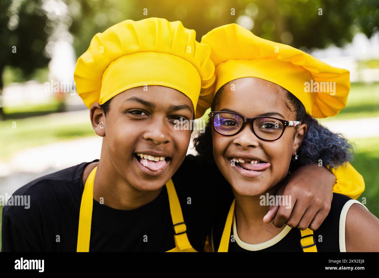 African children cooks in chefs hat and yellow uniforms grimacing and ...