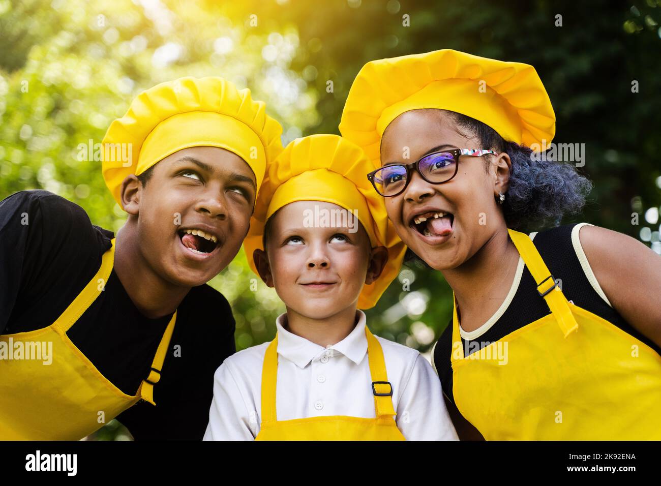 Multinational company of children cooks in yellow uniforms smiling and ...