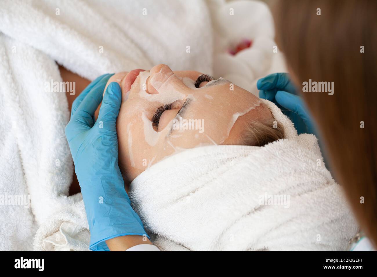 Young woman on a look after face and mask against black dots Stock ...