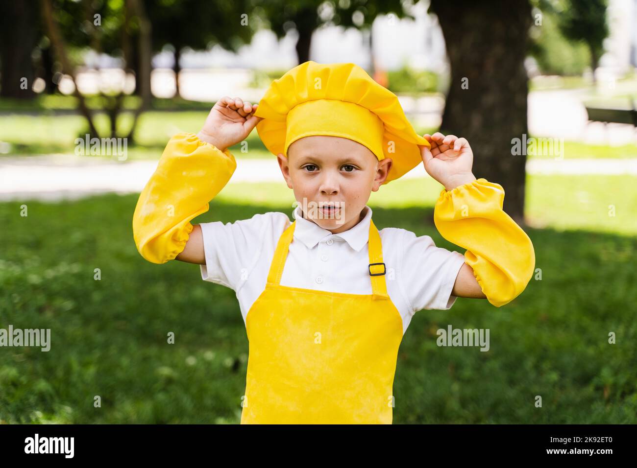 Shocked cook child in yellow chefs hat and apron yellow uniform holding ...