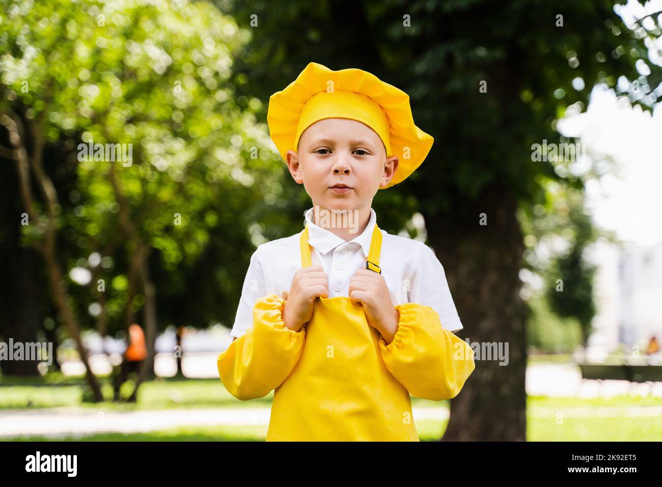 Handsome cook child in yellow chefs hat and apron yellow uniform posing ...