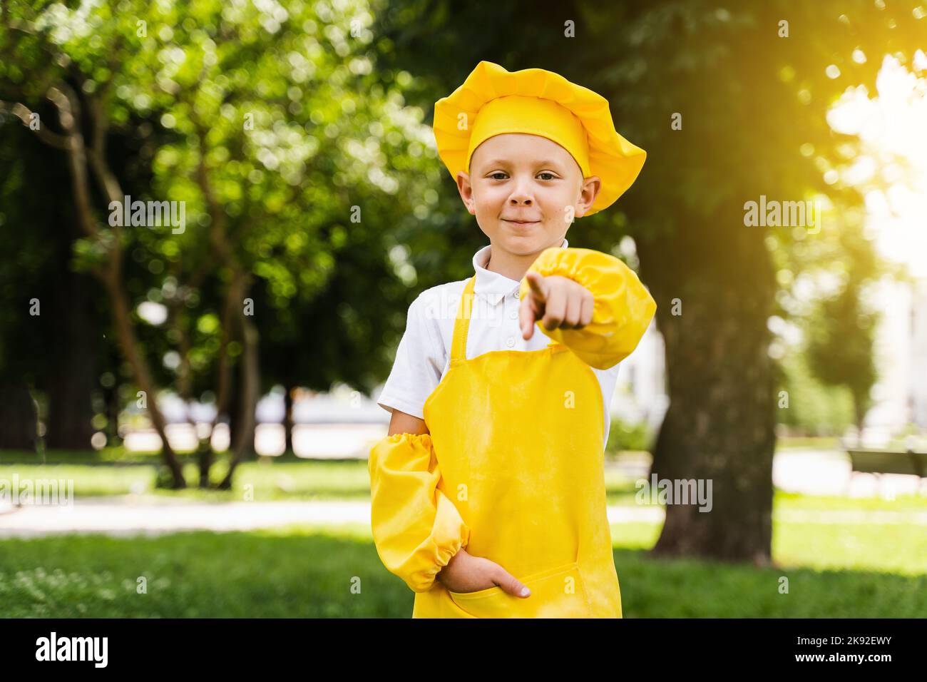 Handsome cook child in yellow chefs hat and apron yellow uniform points ...