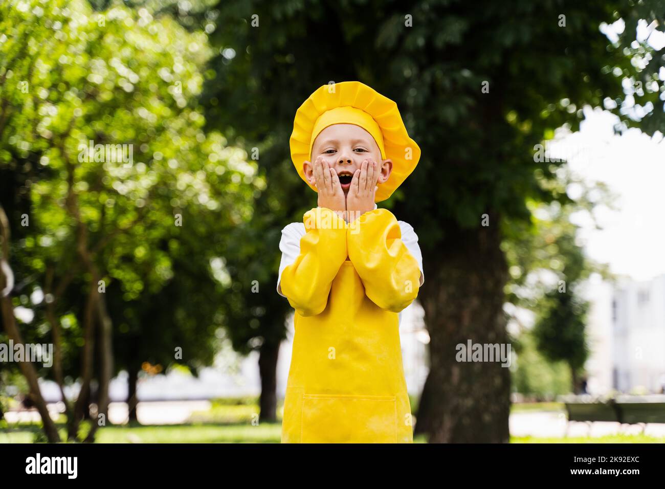 Shocked cook child in yellow chefs hat and apron yellow uniform holding ...