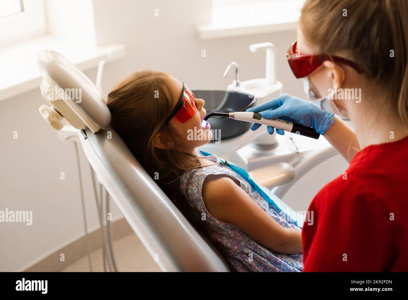 Child dentist treats and removes caries in a patient. Uv illumination ...