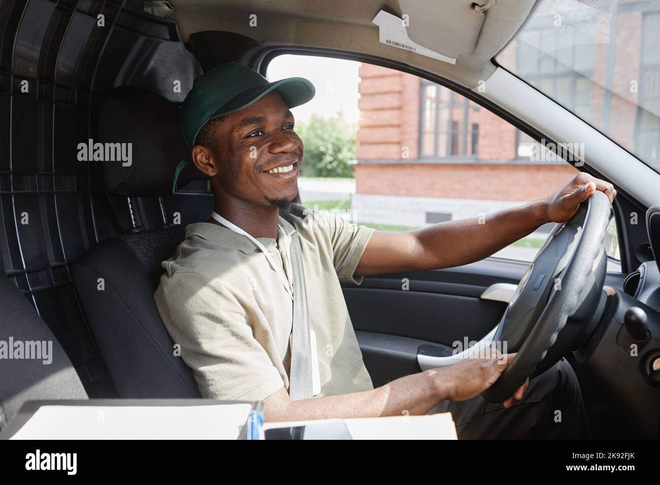 Side view portrait of young black man driving delivery van in sunlight ...